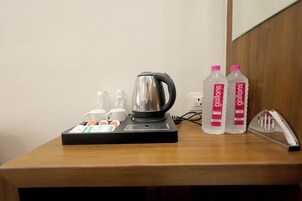 Uma cafeteira, duas garrafas de água e algumas chávenas sobre uma mesa de madeira.