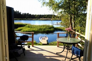 Um deck com vista para um lago, um barco e móveis para área externa.
