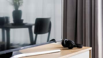 Um par de fones de ouvido sobre uma mesa de madeira com uma janela de vidro e uma planta em vaso ao fundo.