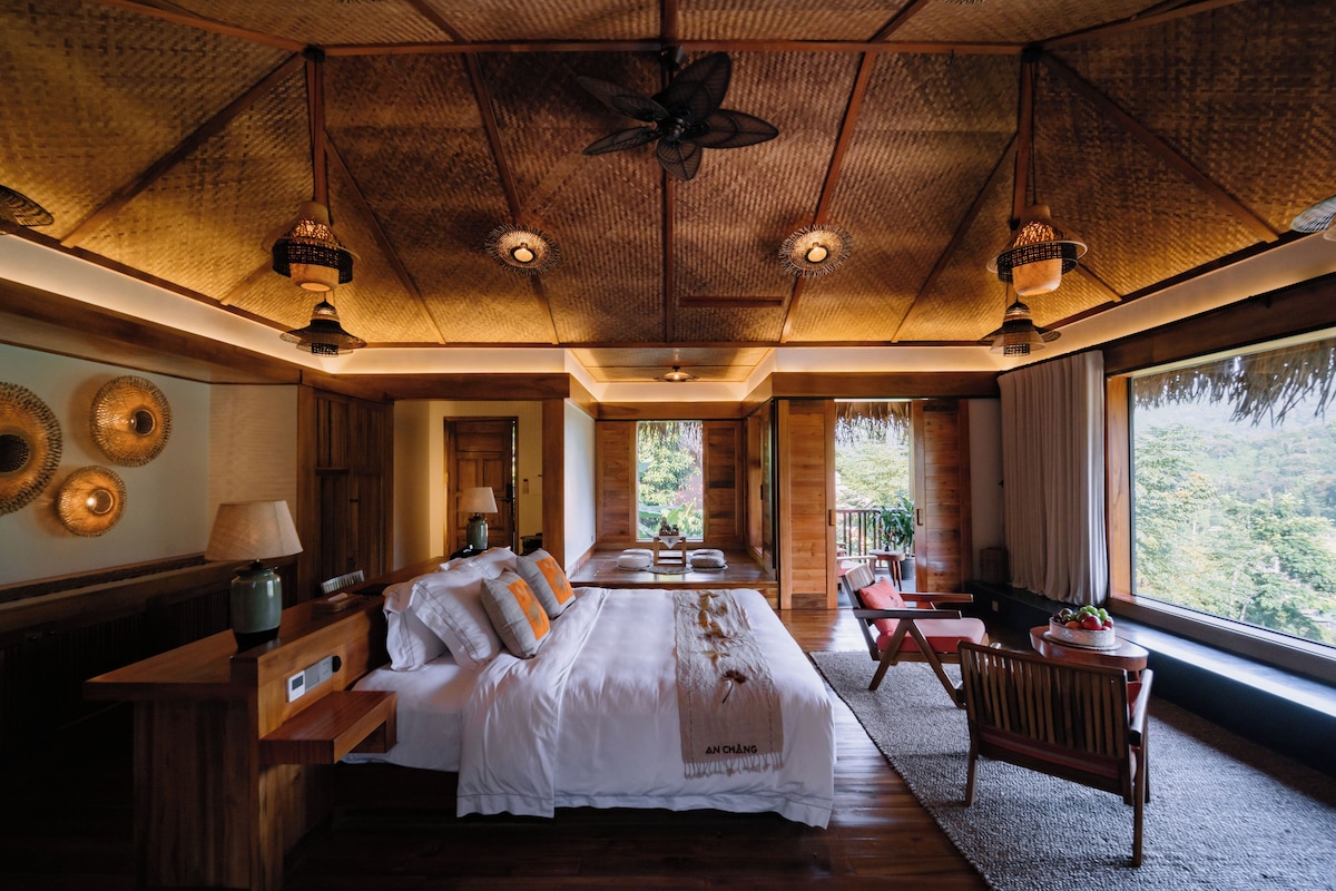 Quarto espaçoso com cama grande, escrivaninha e cadeira. Janela com vista para o exterior.