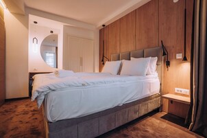 Quarto moderno com cama grande, paredes de painel de madeira, um banco embutido e um espelho.