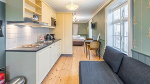 Quarto compacto com cozinha compacta, sofá, mesa de jantar e janela.