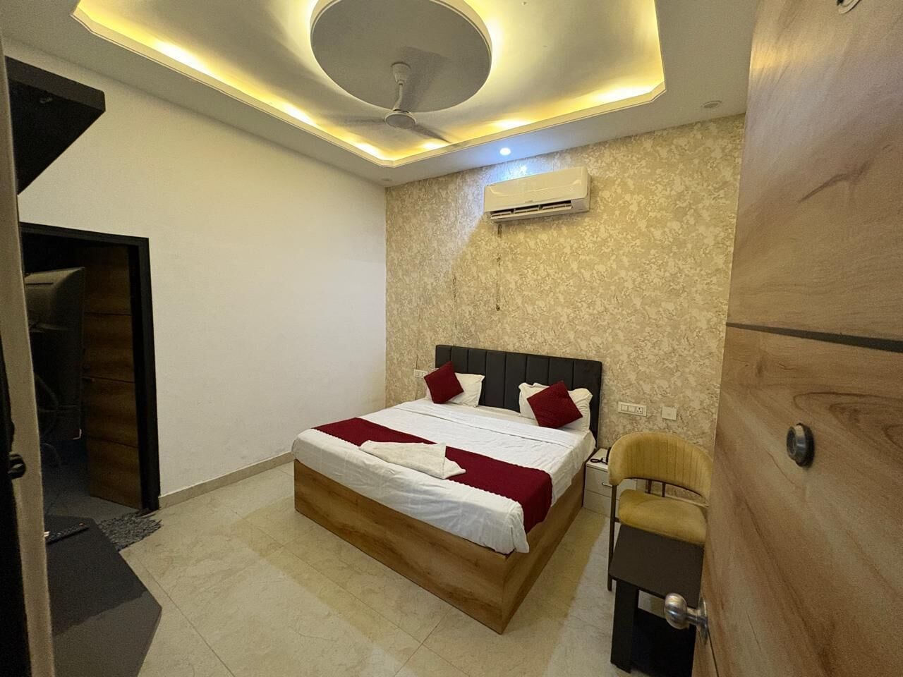 Um quarto com cama, ventoinha no teto, ar condicionado e guarda-roupa de madeira.