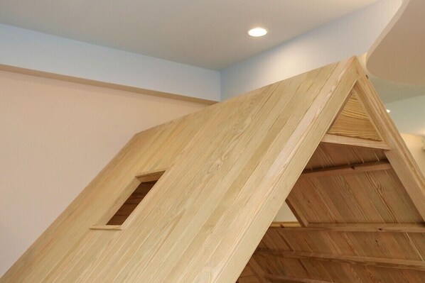 Estrutura de madeira com telhado triangular e uma pequena janela, provavelmente parte do interior de um edifício.