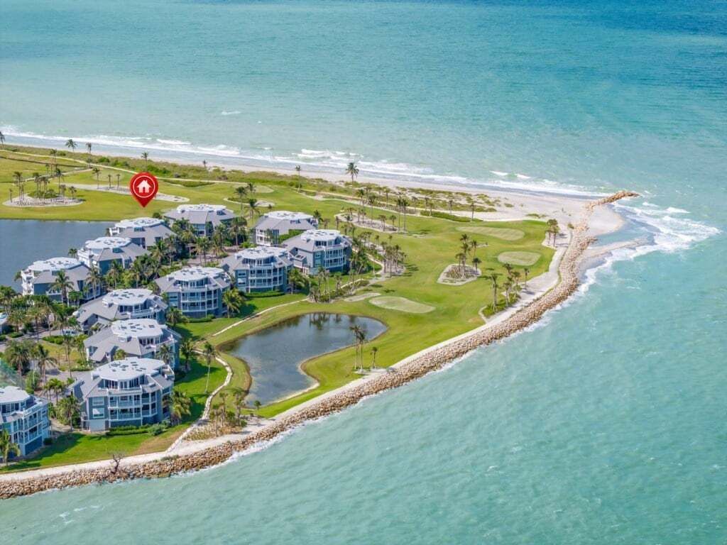 Vista aérea de um resort costeiro com vários edifícios, uma praia e um campo de golfe.
