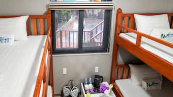 Quarto com beliche, janela, uma mesinha com produtos de higiene e um par de sapatos.
