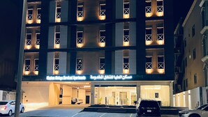 Um hotel com vários andares, janelas iluminadas e entrada no nível da rua.