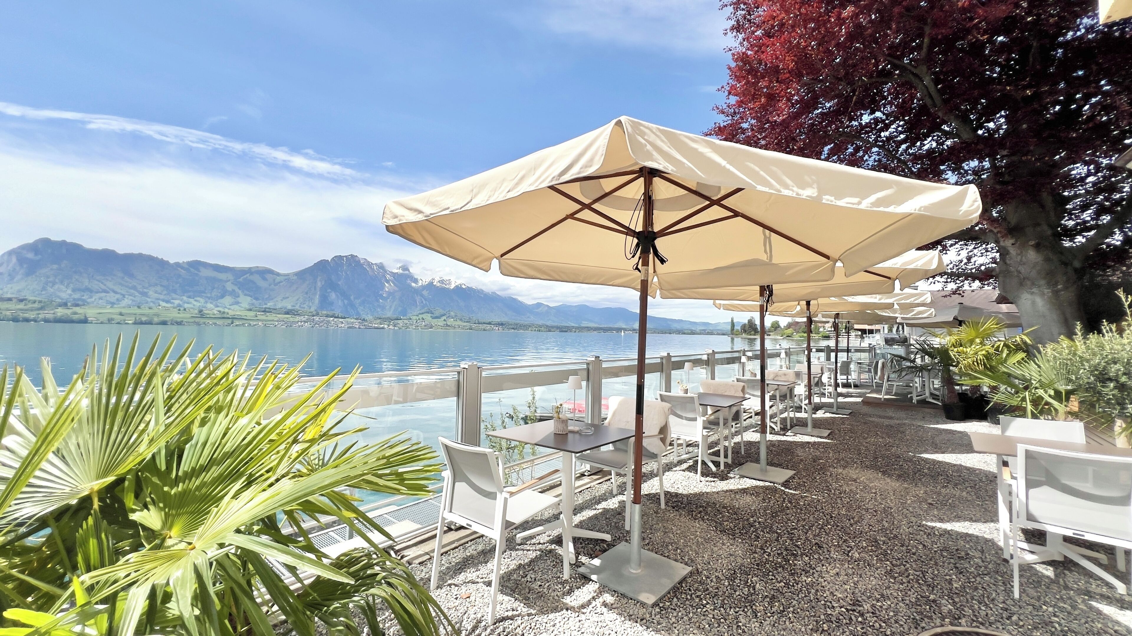 Um terraço com área de estar ao ar livre e vista para um lago e montanhas.