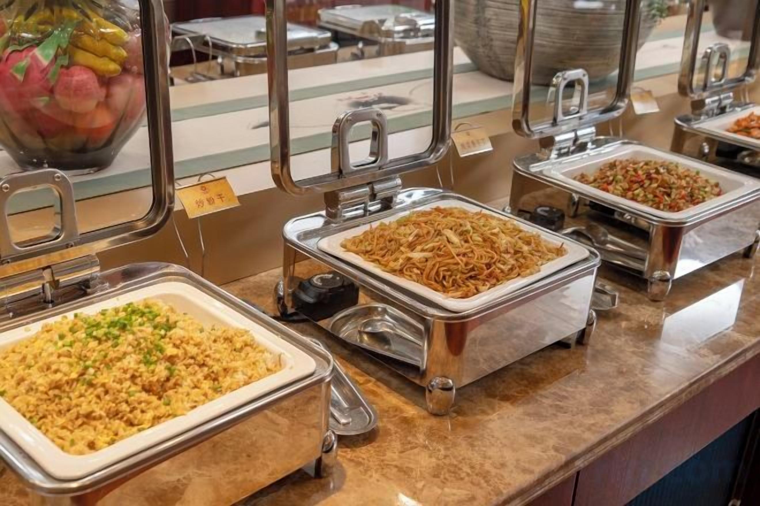 Buffet com várias estações de comida, incluindo um bar de saladas e uma estação de macarrão.