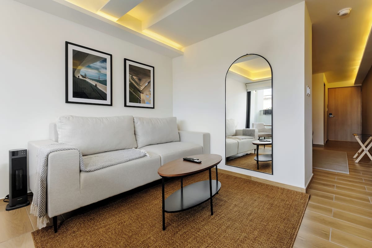 Uma sala de estar moderna com um sofá, uma mesa de centro e duas fotos emolduradas na parede.