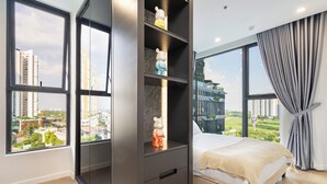 Quarto moderno com uma janela grande, uma cama, uma mesa de cabeceira e uma prateleira com objetos decorativos.