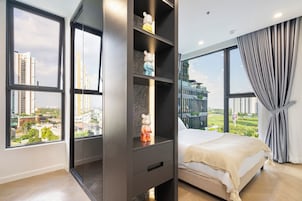 Quarto moderno com uma janela grande, uma cama, uma mesa de cabeceira e uma prateleira com objetos decorativos.