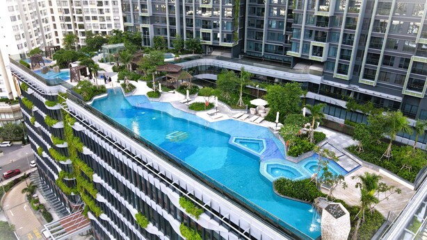 Piscina no terraço com vários níveis de varandas, cercada por vegetação e arquitetura moderna.