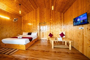 Quarto de cabana de madeira com cama, mesa e televisão na parede.