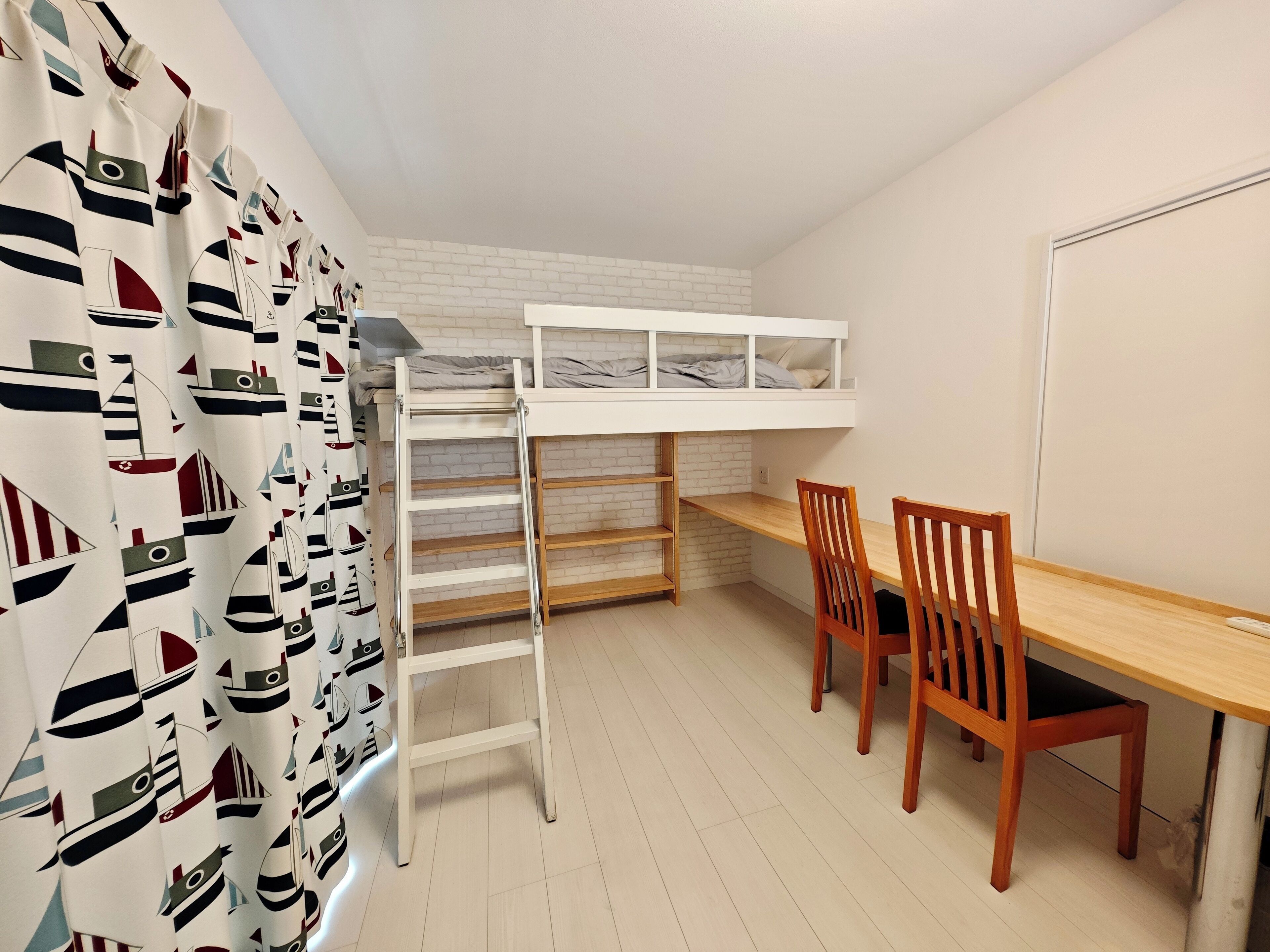 Quarto com uma cama beliche, uma escrivaninha e duas cadeiras.