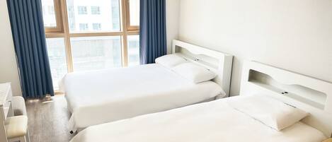Quarto de hotel com duas camas, uma escrivaninha e uma cadeira.
