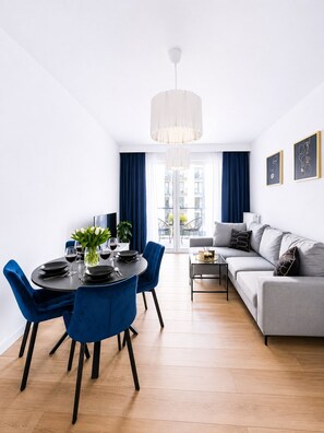 Uma sala de estar moderna com área de jantar, sofá e lustre.