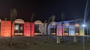 Fileira de contêineres de transporte coloridos, transformados em hotel, com janelas em arco e área externa coberta.