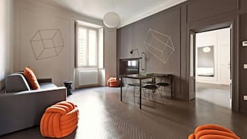 Uma sala de estar moderna com sofá, um banquinho laranja, mesa de jantar e cadeiras.