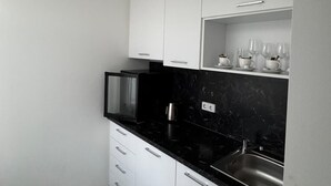 Uma cozinha moderna com armários brancos, bancada preta e pia de aço inoxidável.