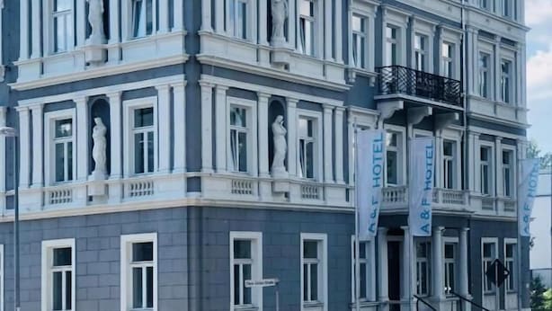 Um edifício de vários andares com arquitetura clássica, apresentando janelas simétricas e estátuas decorativas.