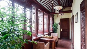 Interior de madeira tradicional com área de refeições, janelas amplas e uma escadaria.