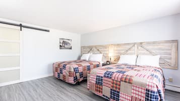 Quarto com duas camas, cada uma com colcha xadrez, cabeceira de madeira e mesa de cabeceira pequena com abajur.