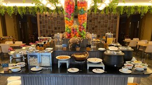 Disposição de buffet com diversos alimentos e uma coluna decorativa de frutas.
