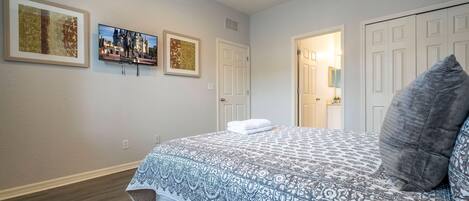 Quarto com uma cama grande, um guarda-roupa e duas imagens emolduradas na parede.