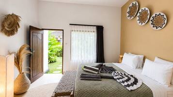Quarto de hotel com cama, mesa de cabeceira, janela com cortinas, porta para um jardim e arte nas paredes.