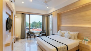 Quarto de hotel moderno com uma cama grande, uma escrivaninha, uma cadeira e uma televisão.