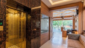 Um hall moderno com elevador de mármore, balcão de recepção e área de estar com vista para o exterior.