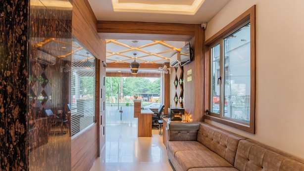 Interior moderno com uma mesa de recepção de madeira, área de estar com sofá e uma grande janela com vista para o exterior.