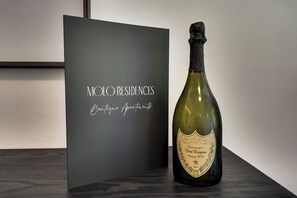 Uma garrafa de champanhe Dom Pérignon e uma placa preta com a inscrição 'Molo Residences Boutique Apartments'.