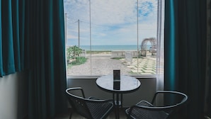 Quarto com vista para a praia, com uma mesa redonda e duas cadeiras.