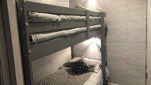 Uma cama beliche com cabeceira e peseira, um travesseiro e um cobertor na cama inferior.