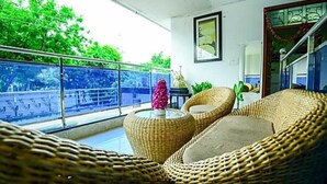 Varanda com móveis de vime e vista para um corrimão azul.