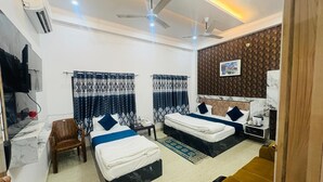 Quarto de hotel com duas camas, televisão, escrivaninha e ventilador de teto.