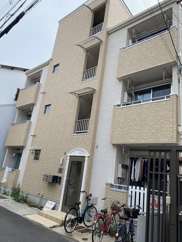 Um edifício residencial com várias andares, varandas, porta de entrada e bicicletas estacionadas na frente.