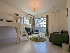 Uma sala de estar moderna com uma cama beliche, um sofá verde, uma mesinha e um candelabro.