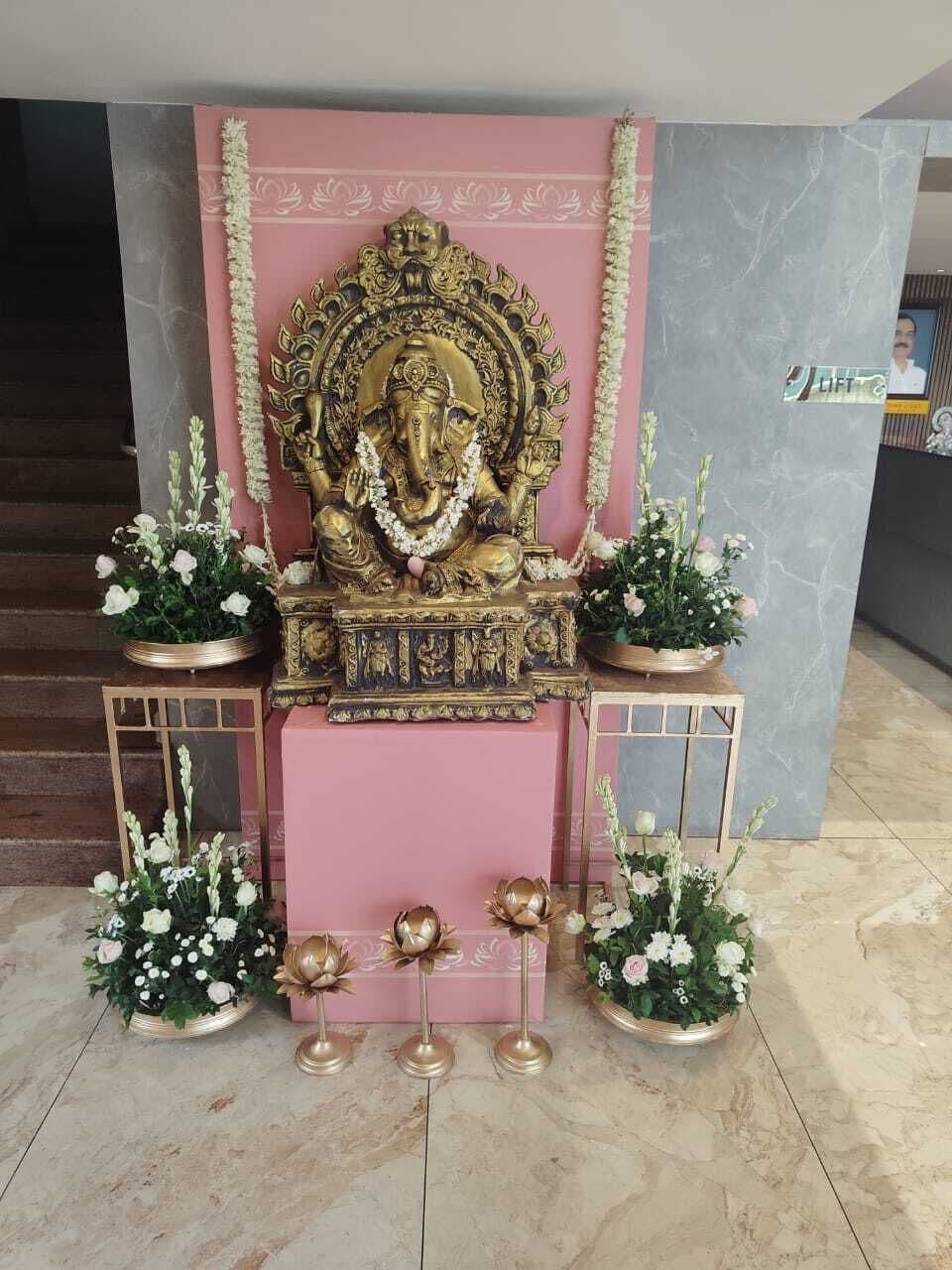 Santuário com uma divindade, flores e um fundo rosa.
