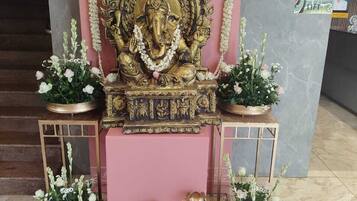 Santuário com uma divindade, flores e um fundo rosa.