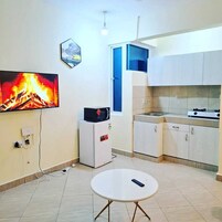 Uma cozinha compacta com uma mesa de jantar, uma geladeira e uma TV fixada na parede.