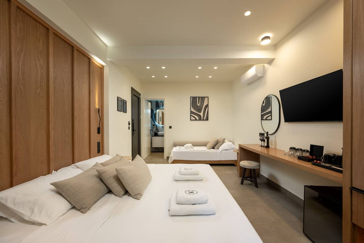 Quarto de hotel moderno com uma cama grande, uma escrivaninha e uma televisão.