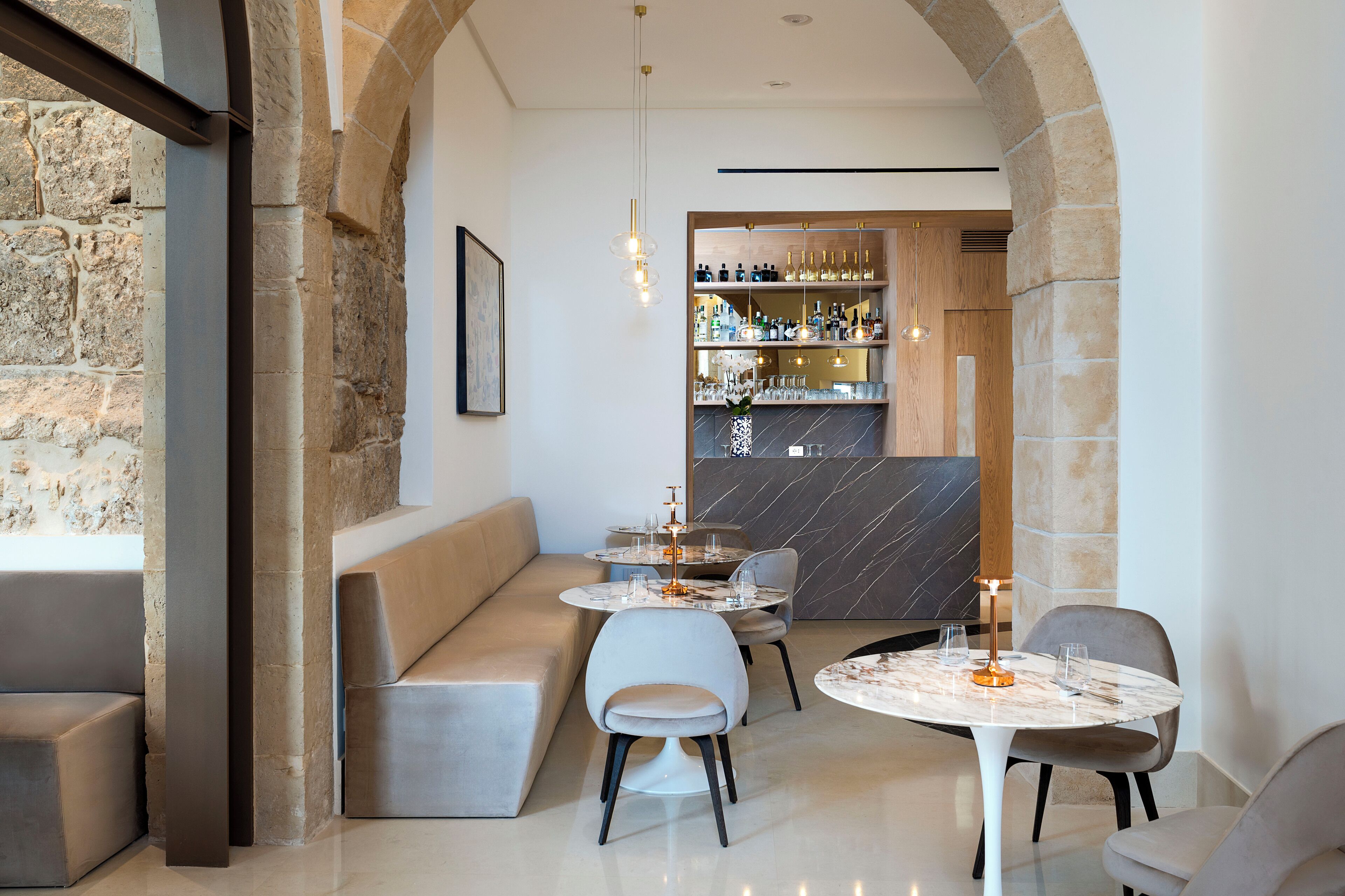 Um interior moderno com área de bar, assentos e bancada de mármore.