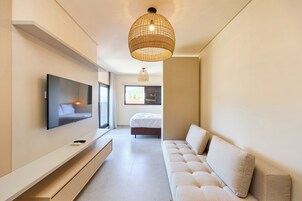 Quarto moderno com televisão, sofá e uma janela grande.