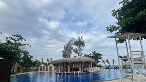 Piscina com espreguiçadeiras e uma estrutura de telhado de palha.