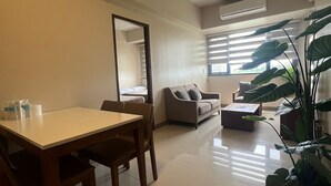 Uma sala de estar espaçosa com uma mesa de jantar, sofá e uma grande planta em vaso.