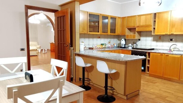Uma cozinha com armários de madeira, bancada de granito e uma ilha central com banquetas.