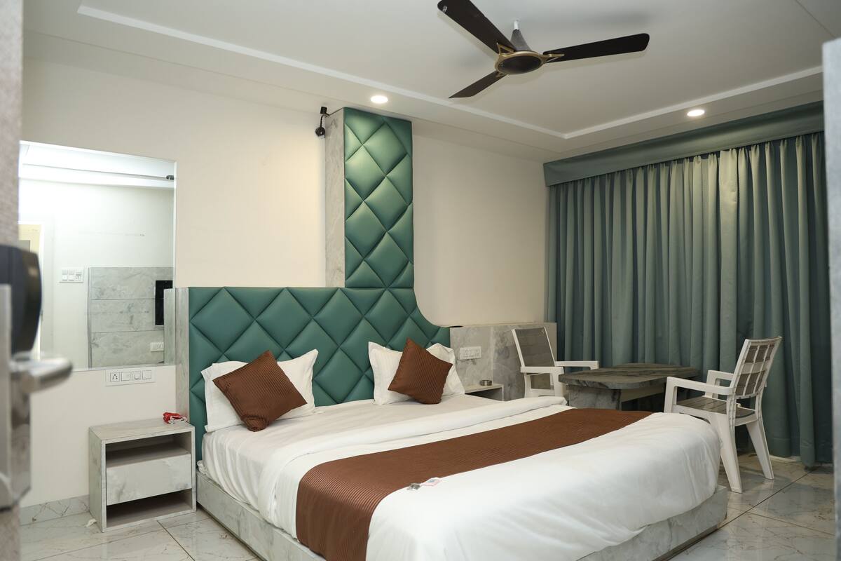 Quarto de hotel moderno com uma cama grande, uma escrivaninha e um ventilador de teto.